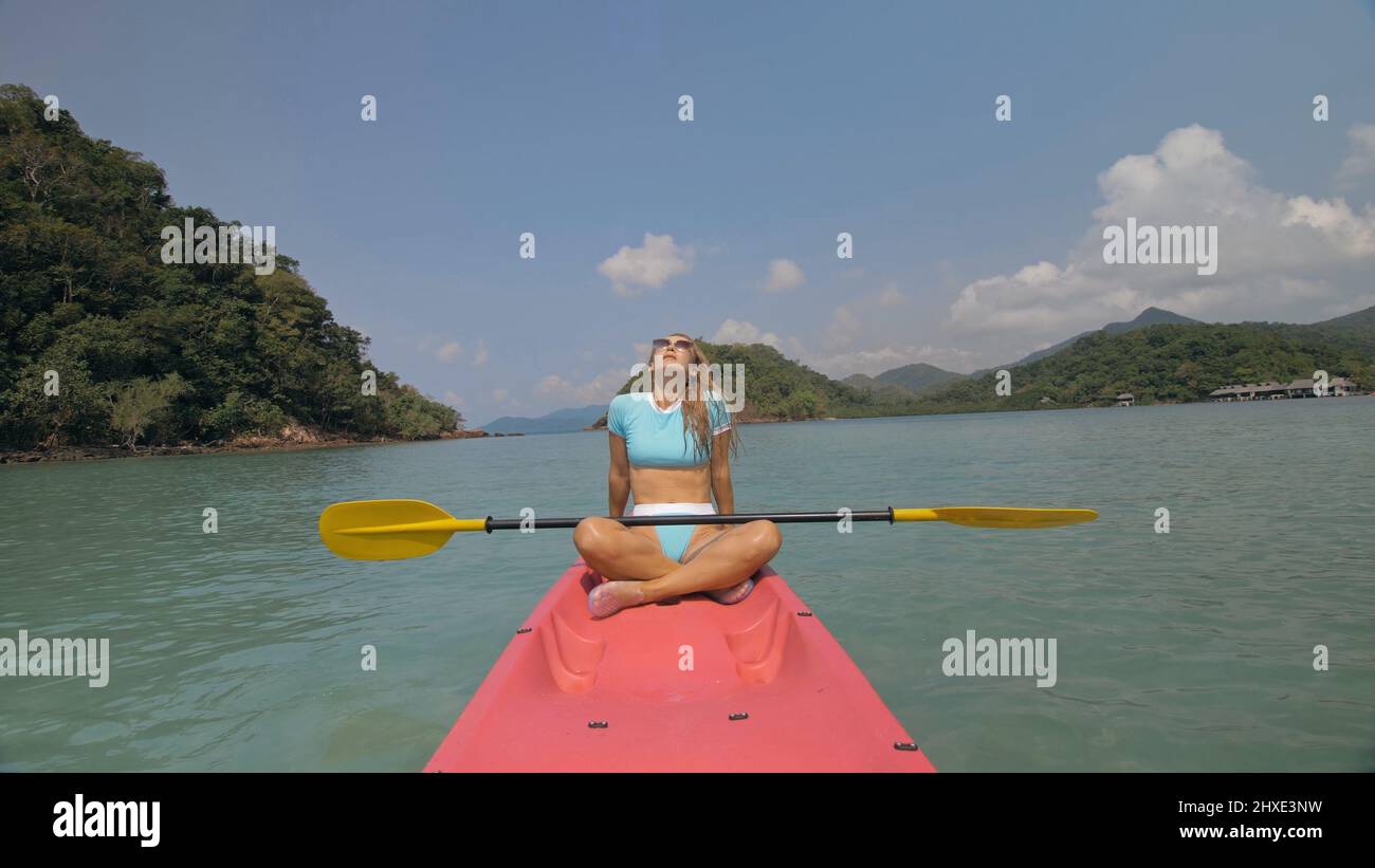 Attractive sportive blonde woman with sunglasses rows pink plastic ...