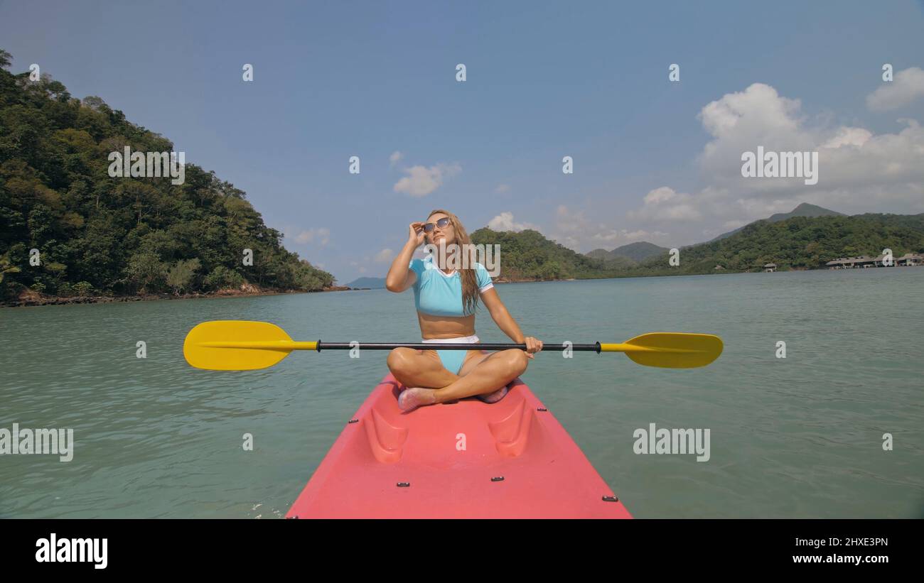 Attractive sportive blonde woman with sunglasses rows pink plastic ...