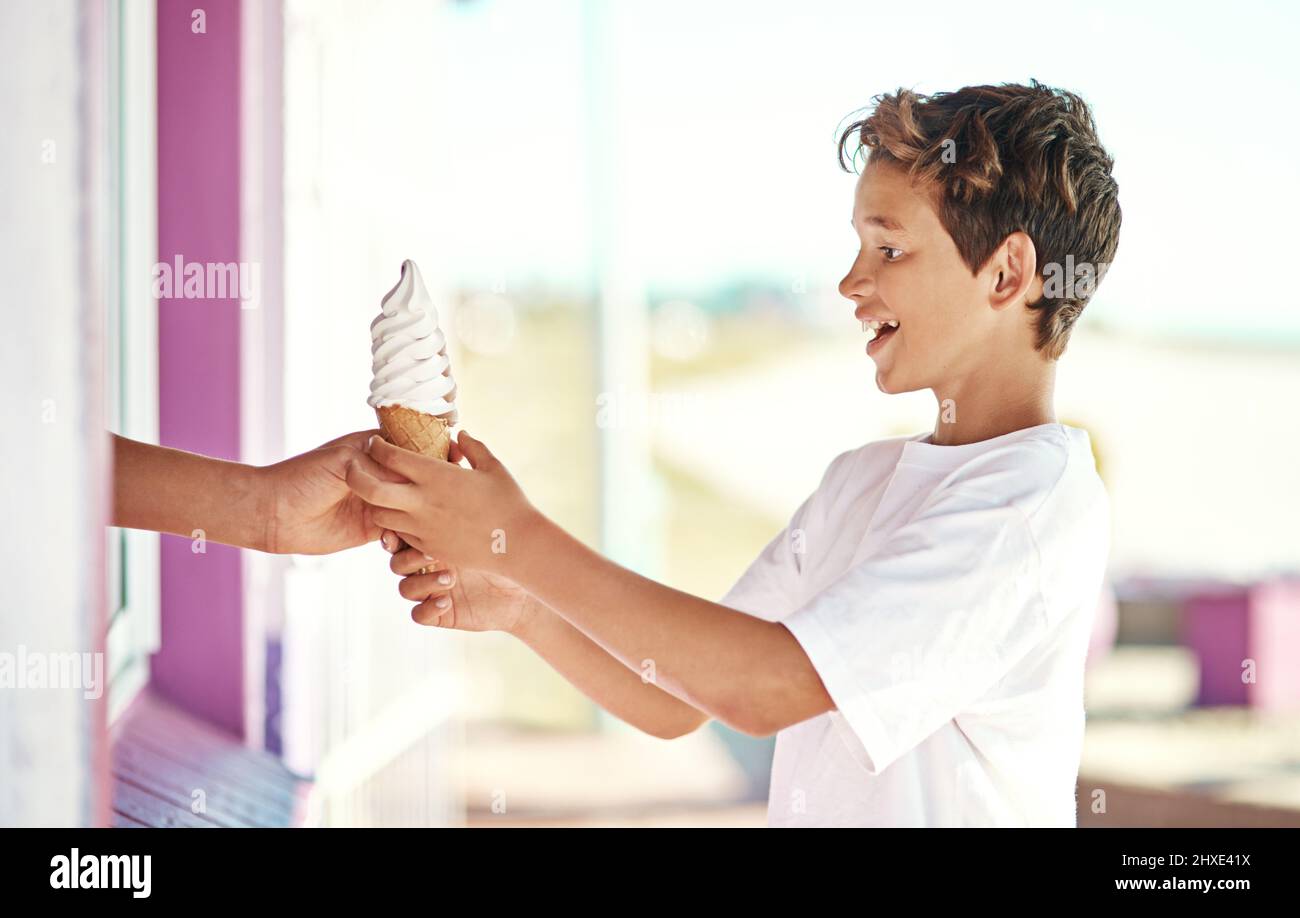 One word yum. Shot of a happy young boy getting an ice-cream cone from ...