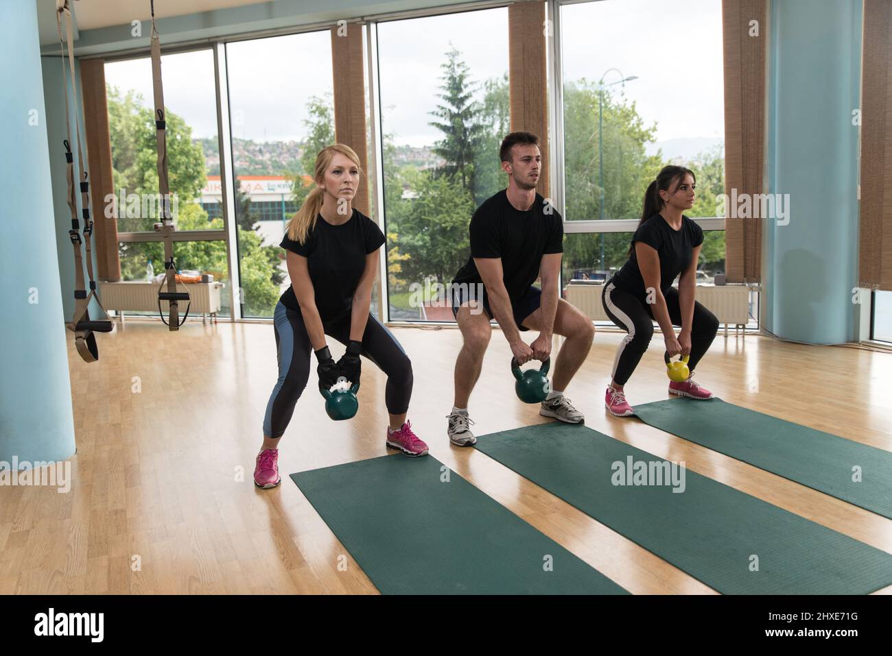 Fitness Group of People Doing Powerlift Exercises With Kettlebells in a ...