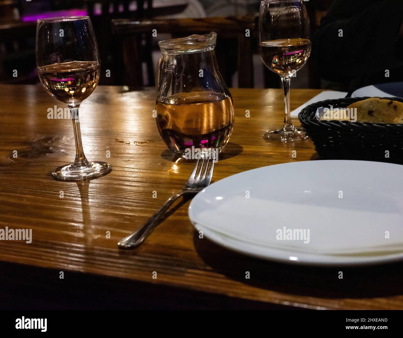 restaurant table with wine carafe and glasses with garlic bread in a ...