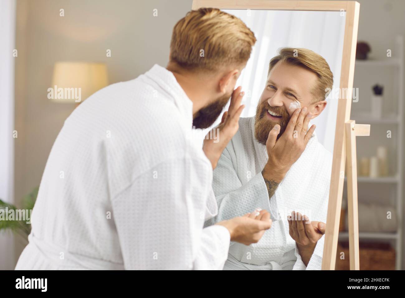 Smiling man apply facial cream do beauty procedures Stock Photo - Alamy