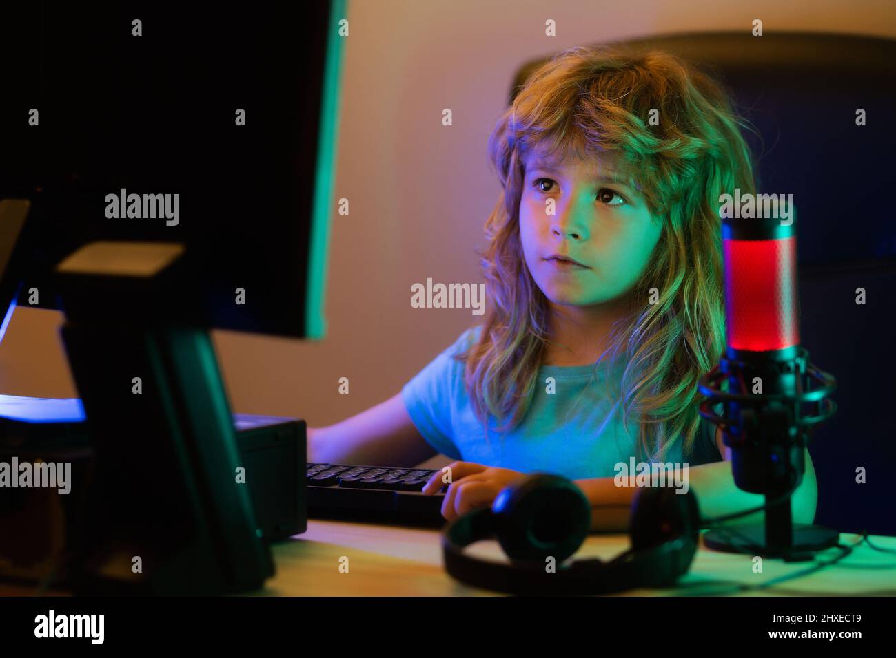 Child with computer late at night. Neon blue light. Little hacker ...