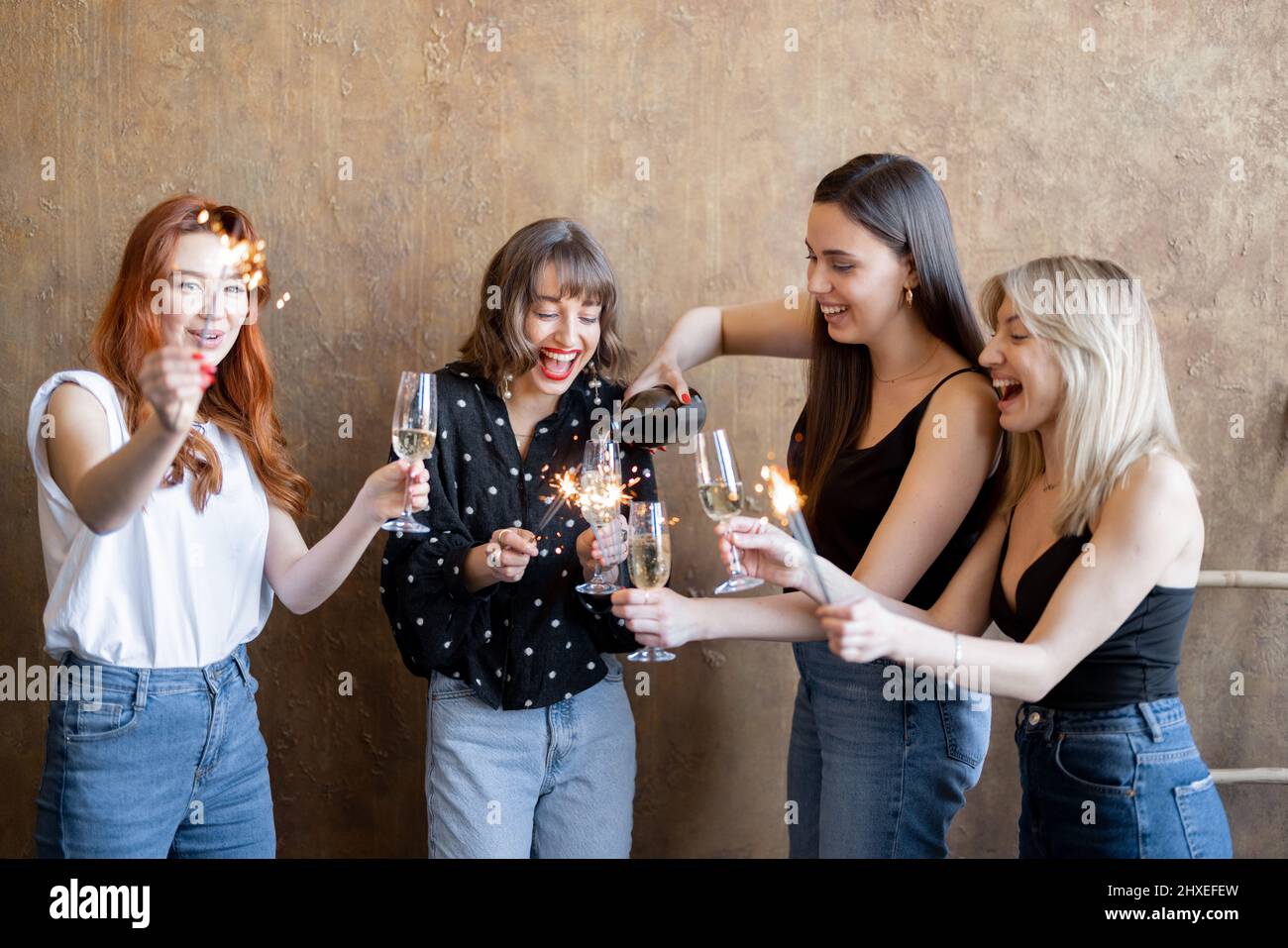 Group of young adult girlfriends drinking sparkling wine and firing ...