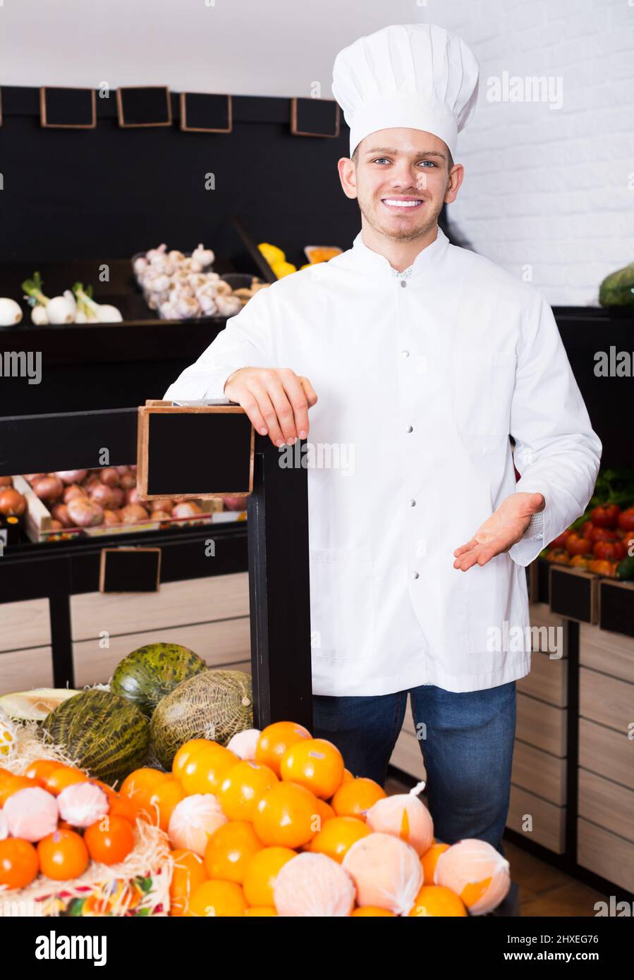 Young cheerful male cook choosing fruits in grocery shop Stock Photo ...