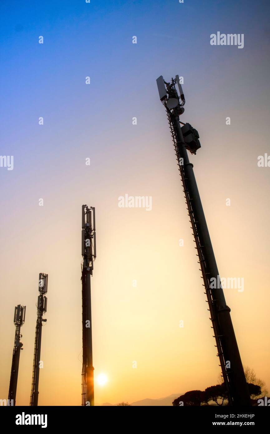 Sunrise photo shoot of mobile phone poles backlit image Stock Photo - Alamy