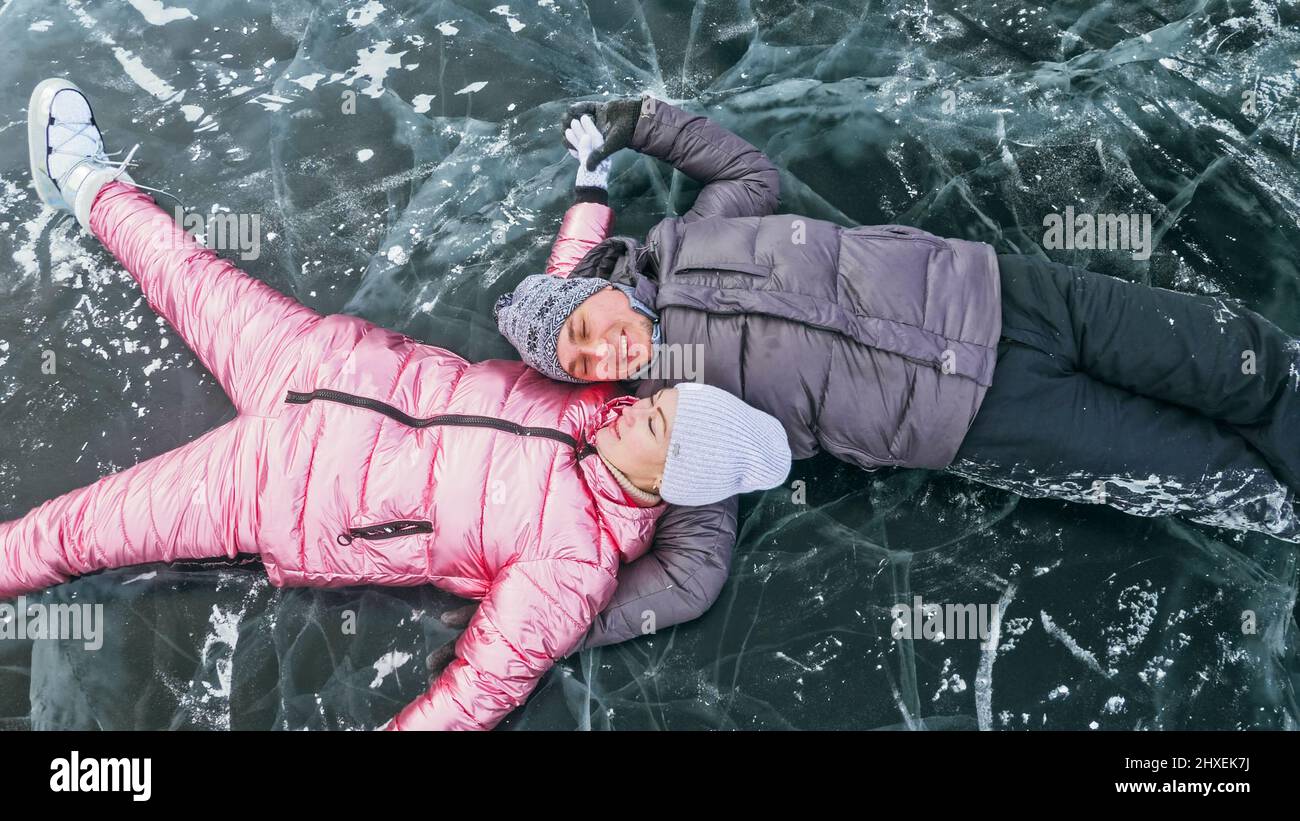 Couple has fun winter walk against background of ice of frozen lake ...