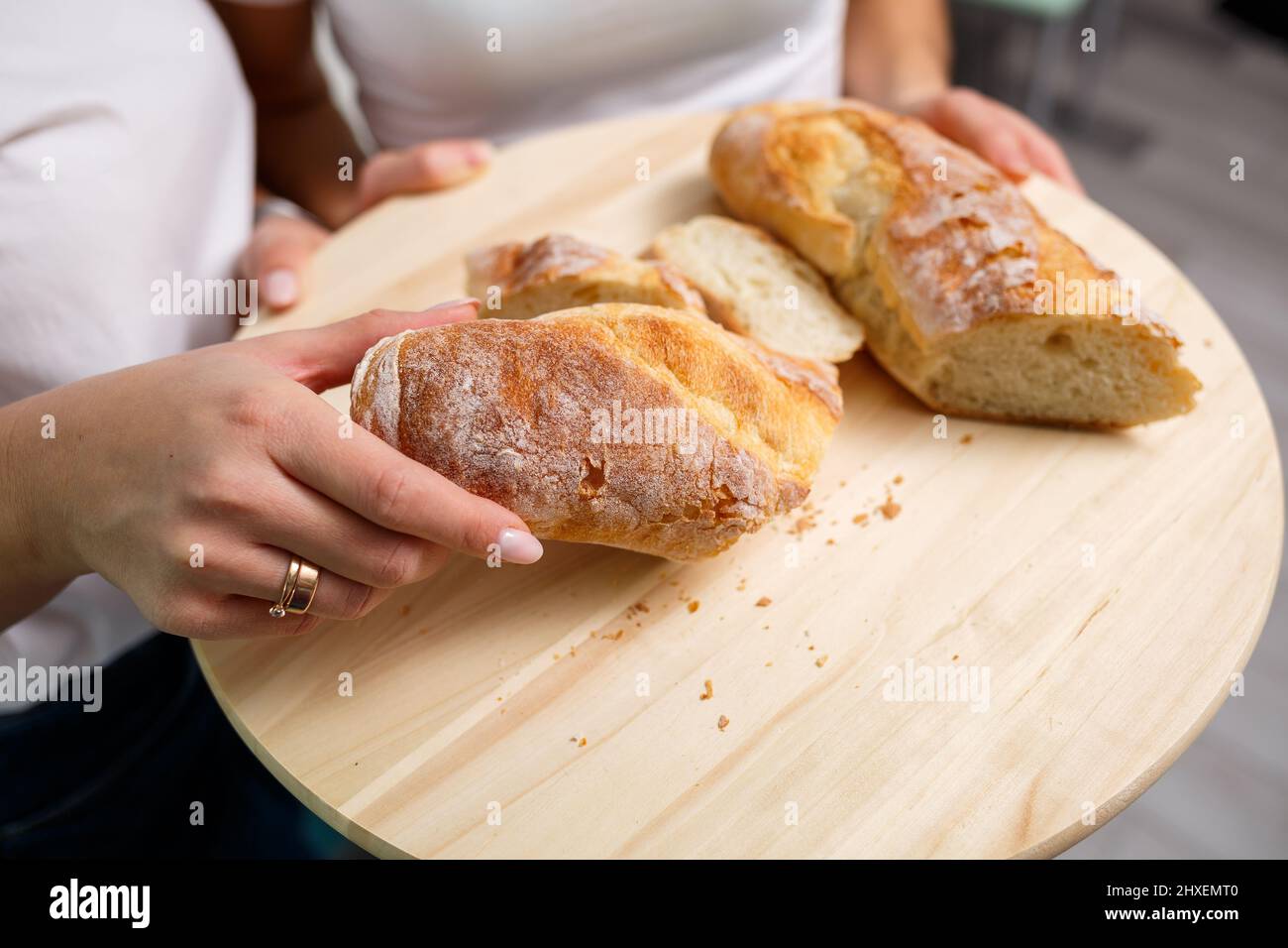 Baker's hands break hot fresh wheat bread into two halves, crunch and ...