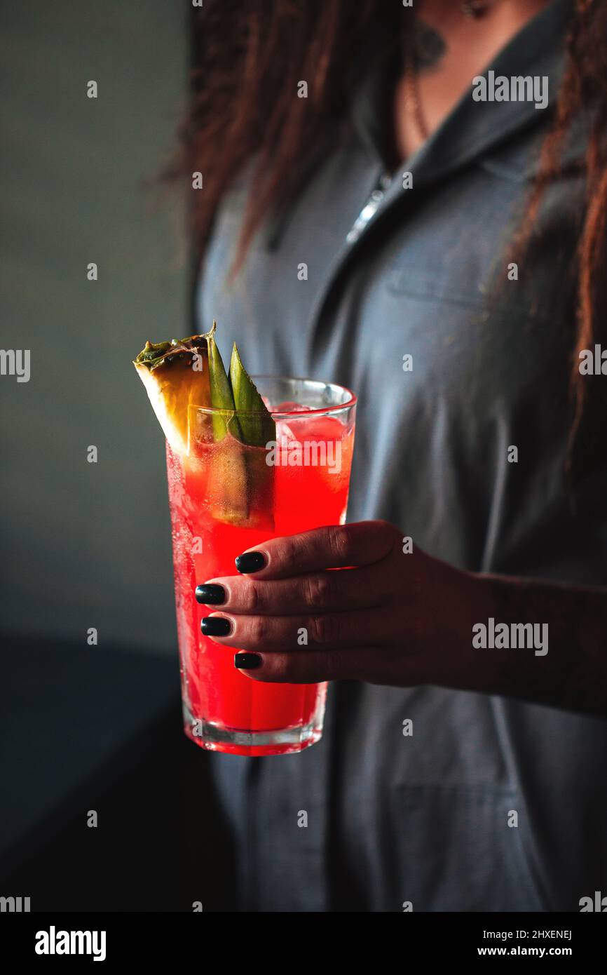 Woman holding red cocktail in a highball with ice Stock Photo - Alamy