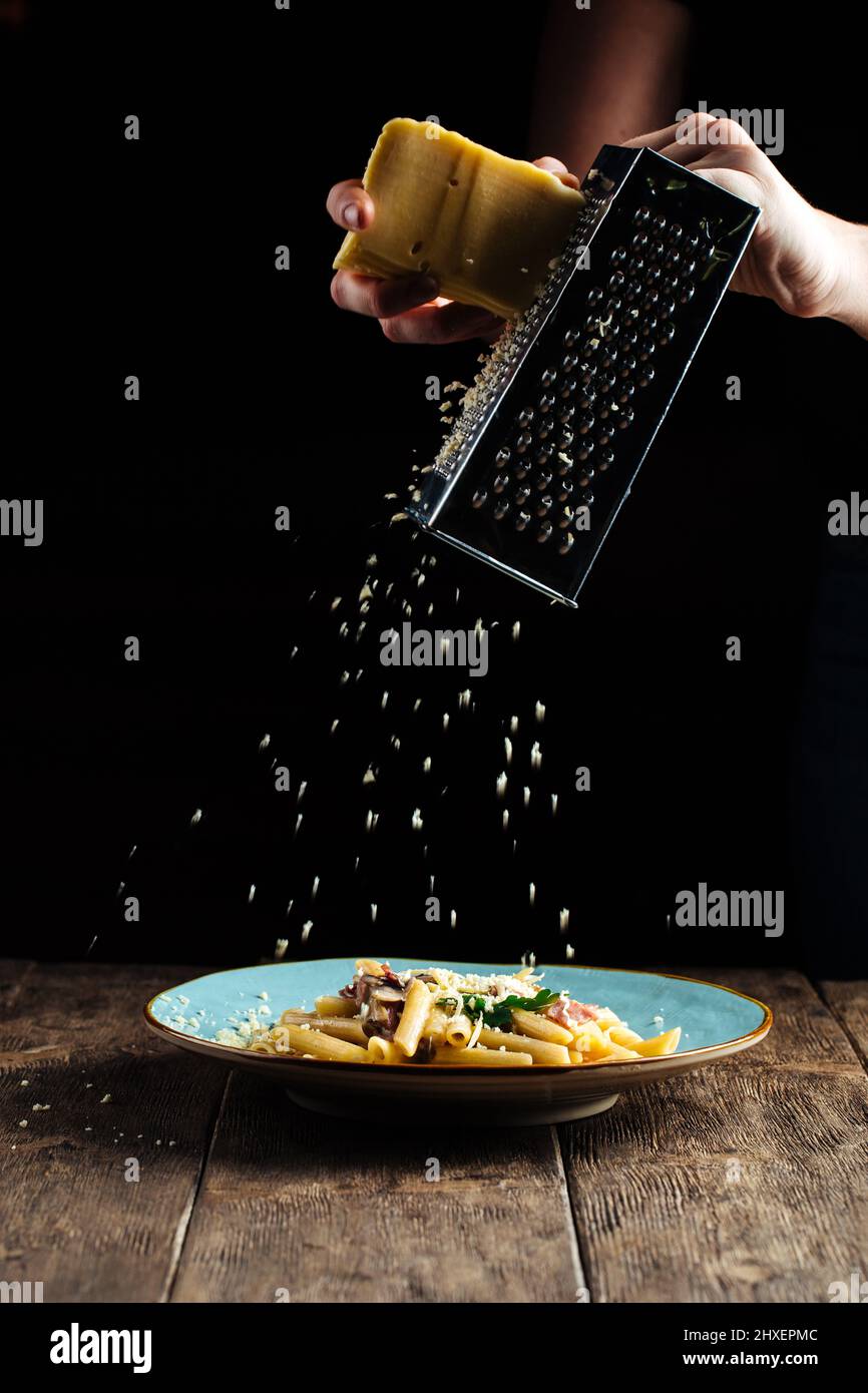 Hands grating cheese over the pasta dish Stock Photo - Alamy