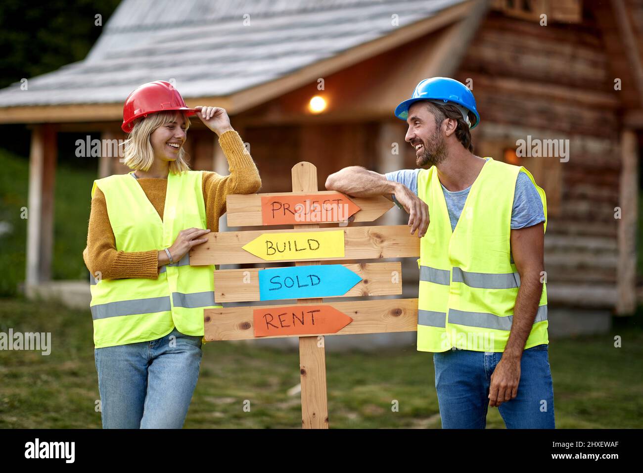 Smiling young construction couple with wooden board.wooden house ...