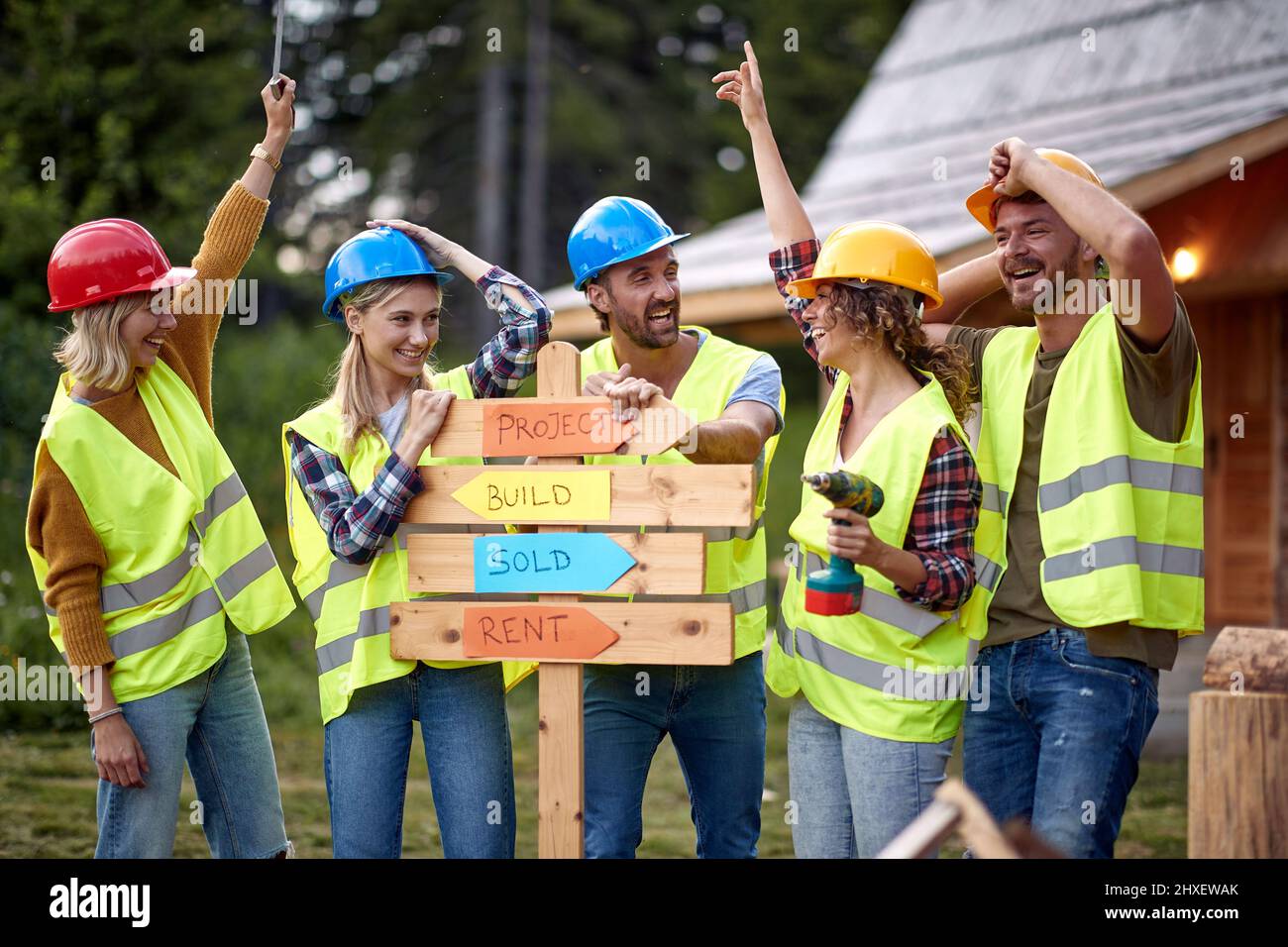 teamwork smiling construction people with wooden board.wooden house ...