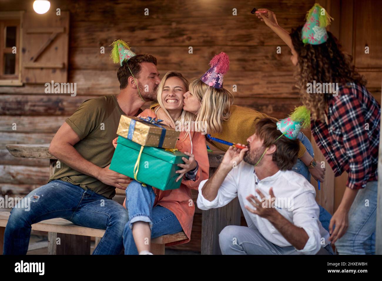 Smiling friends celebration birthday in front of wooden cottage on the ...