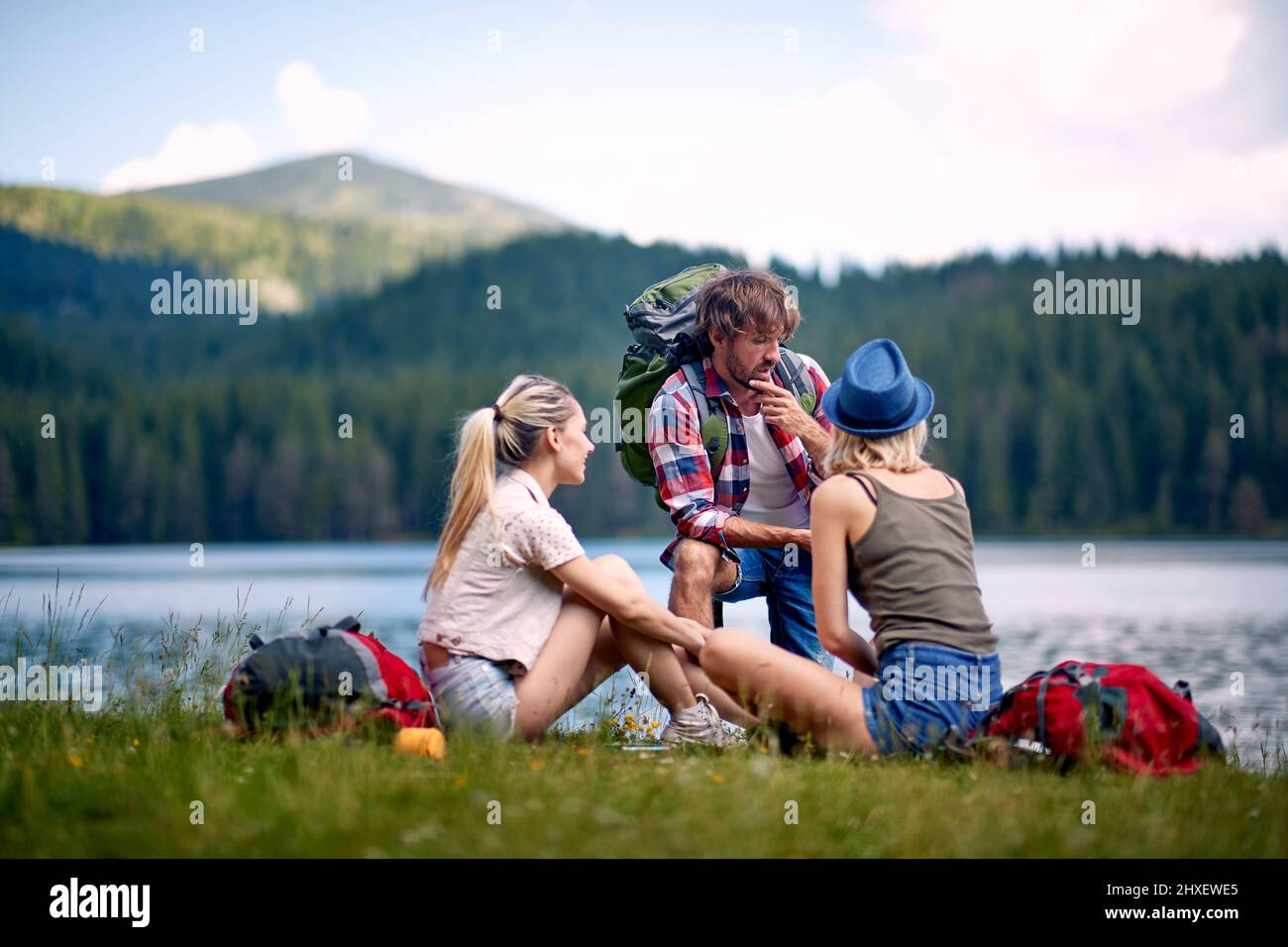 Friends in front of lake looking at map. Backpacker showing map to ...
