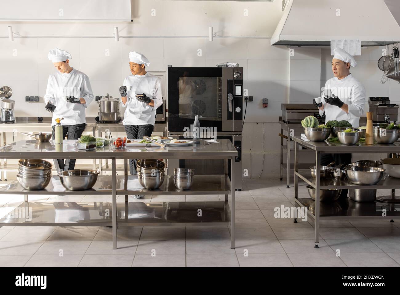 Group of cooks using phones and drinking coffee during a break in the ...