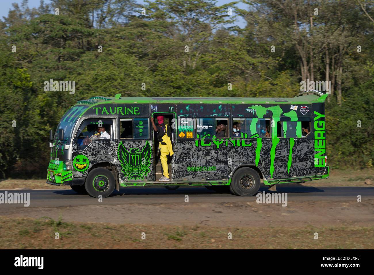Bus with customised paintwork driving along Magadi Road, Langata. Many ...