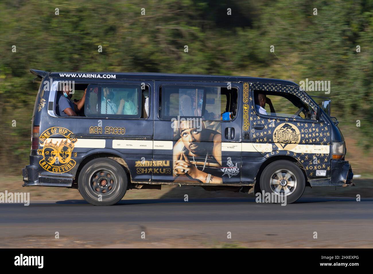 Bus with customised paintwork driving along Magadi Road, Langata. Many ...