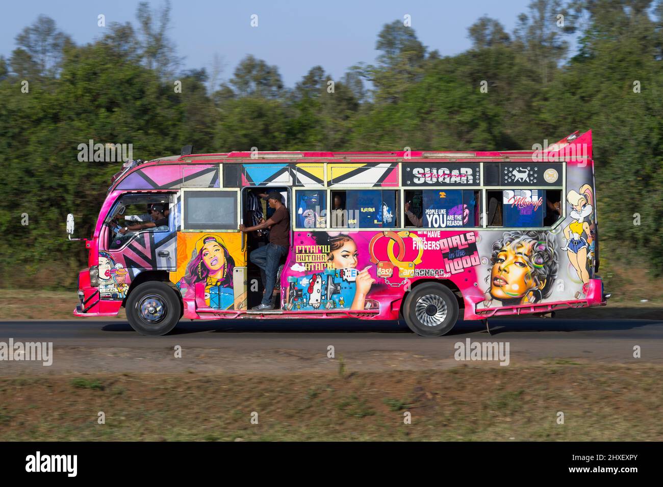 Bus with customised paintwork driving along Magadi Road, Langata. Many buses in Nairobi have ...
