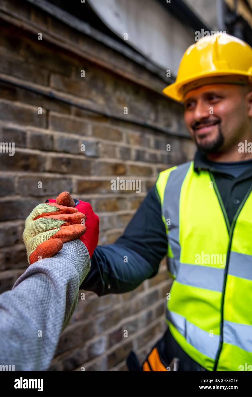 A handsome, happy, smiling construction worker shaking hands with a ...