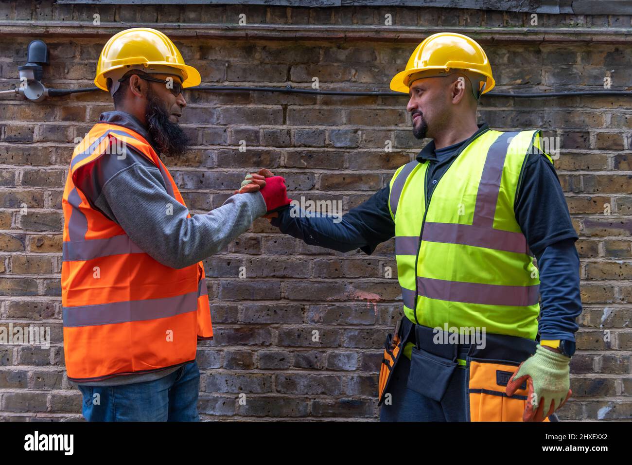 friendly, happy, smiling construction workers greeting and shaking ...