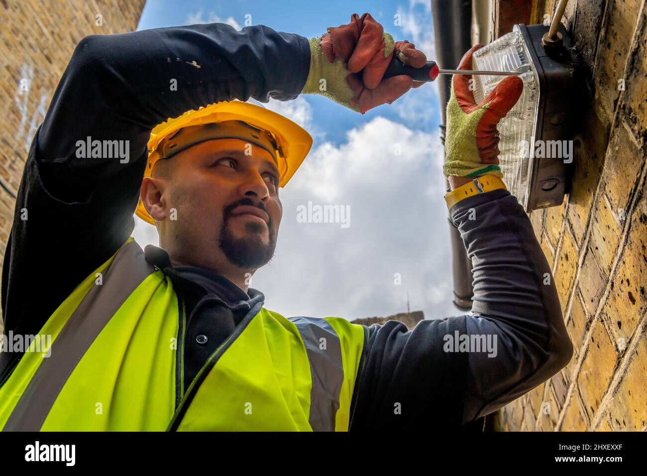 A construction worker fitting outdoor lighting Stock Photo - Alamy