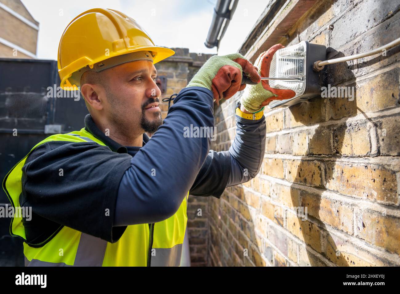 A construction worker fitting outdoor lighting Stock Photo - Alamy