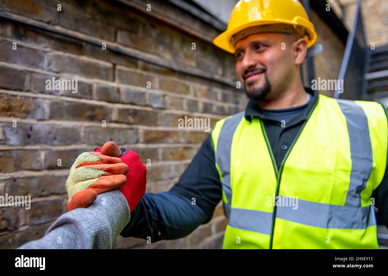 A handsome, happy, smiling construction worker shaking hands with a ...
