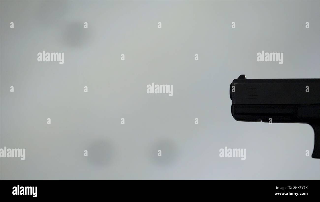 Close profile of man holding a 9 mm handgun, then takes a shot. Man ...