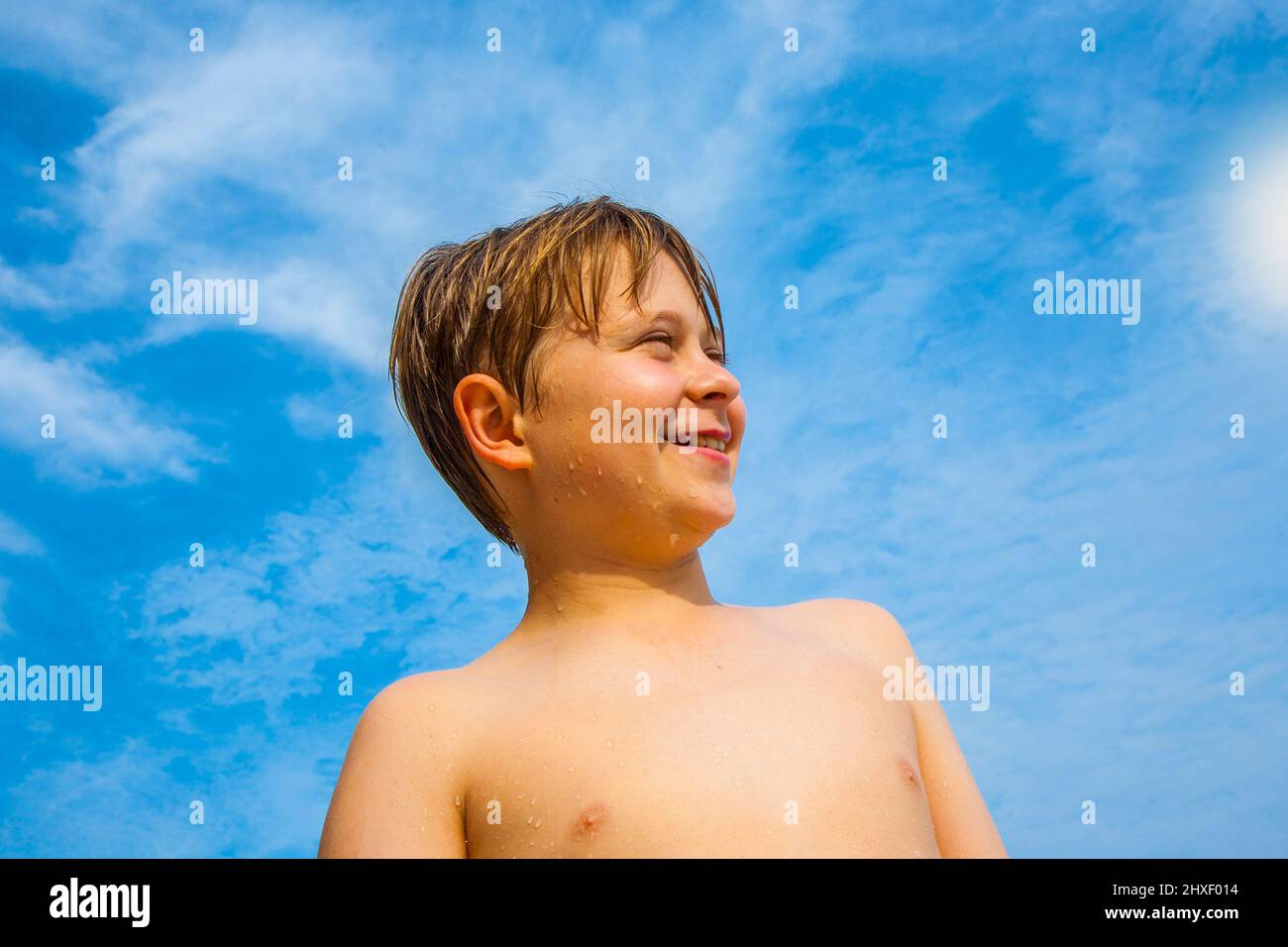 happy young boy with brown hair and eyes enyoys the tropical beach ...