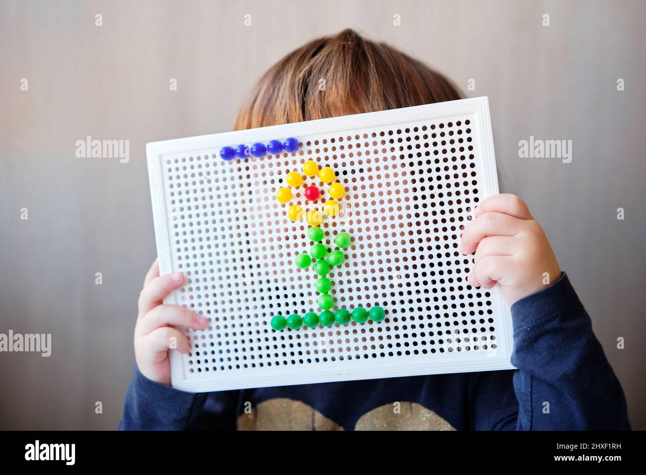 A little girl plays at a table in a multicolored plastic mosaic ...