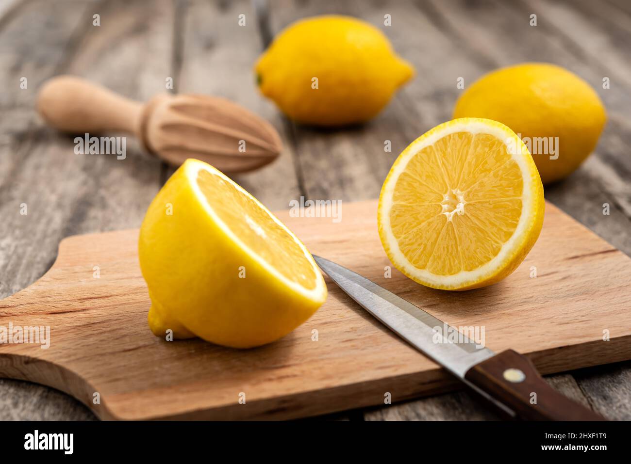 Fresh lemon cut in half with knife on wooden cutting board Stock Photo ...