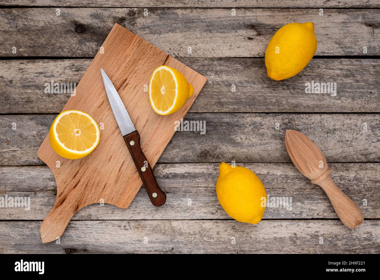 Fresh lemon cut in half with knife on wooden cutting board. Top view ...