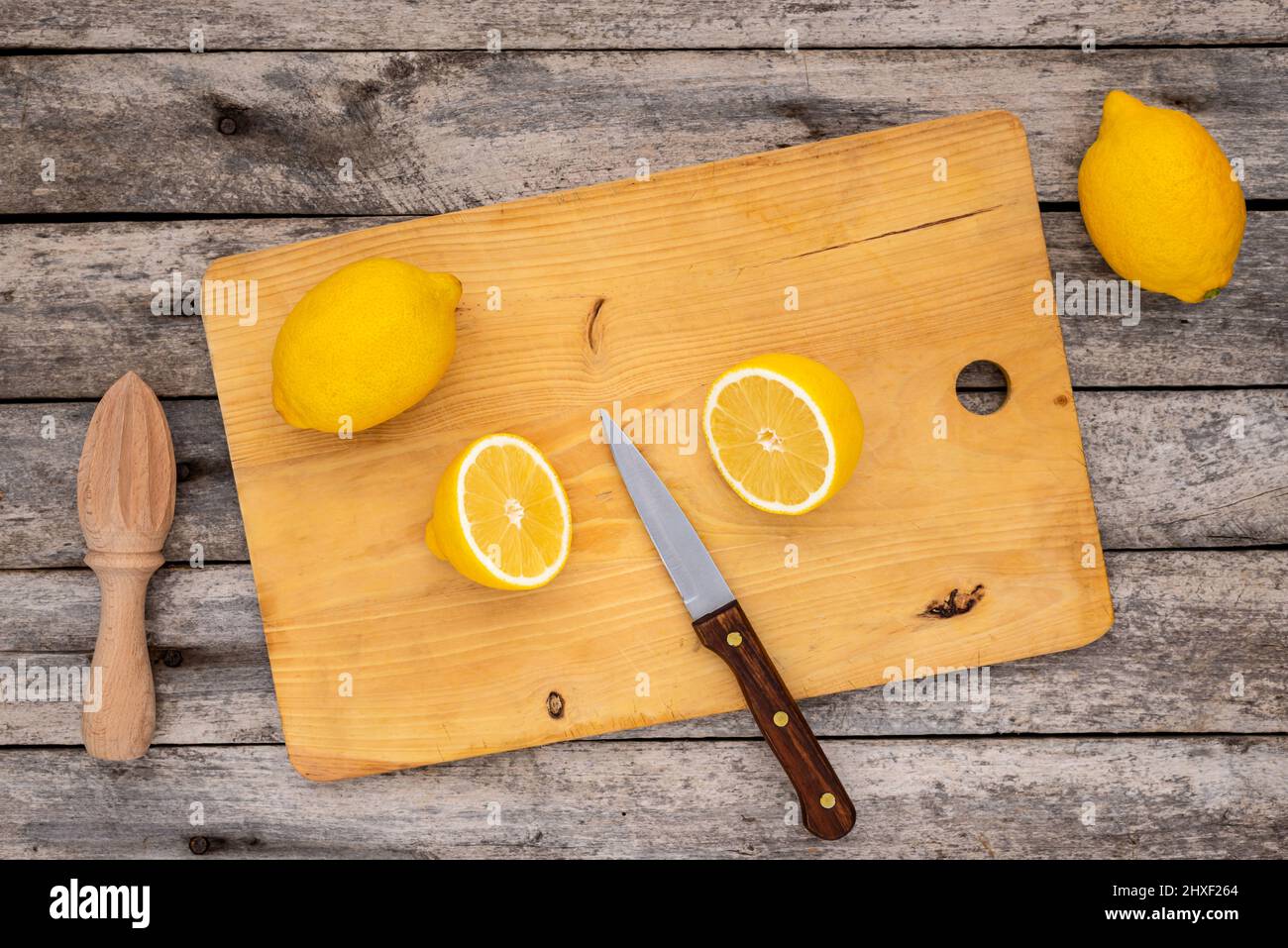 Fresh lemon cut in half with knife on wooden cutting board. Top view ...