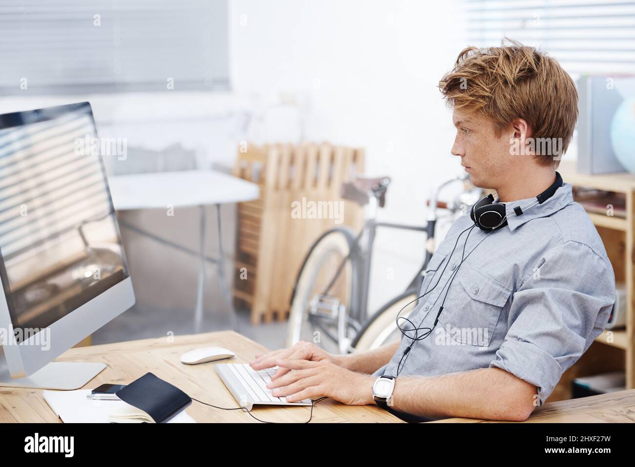 Hes hard at work. A young designer using his computer while sitting in ...