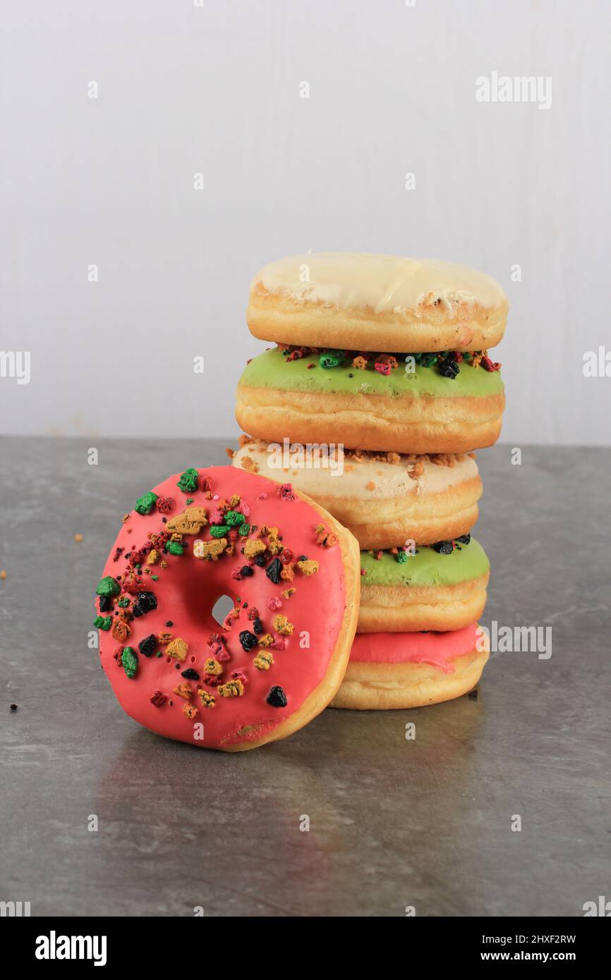Stacked Coclorful Glazed Donut on Cement Table, White Background Stock ...