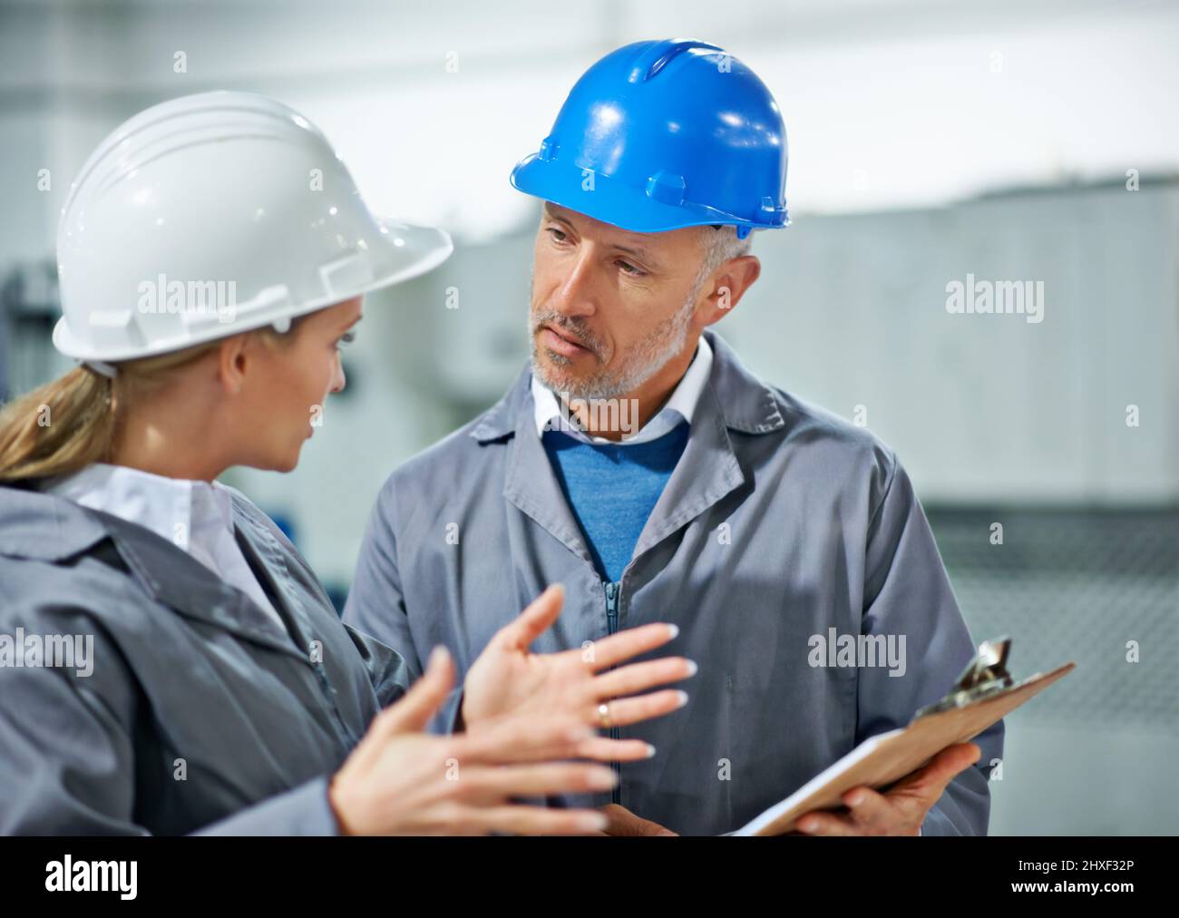 Communication takes practice. Two factory employees wearing hardhats ...