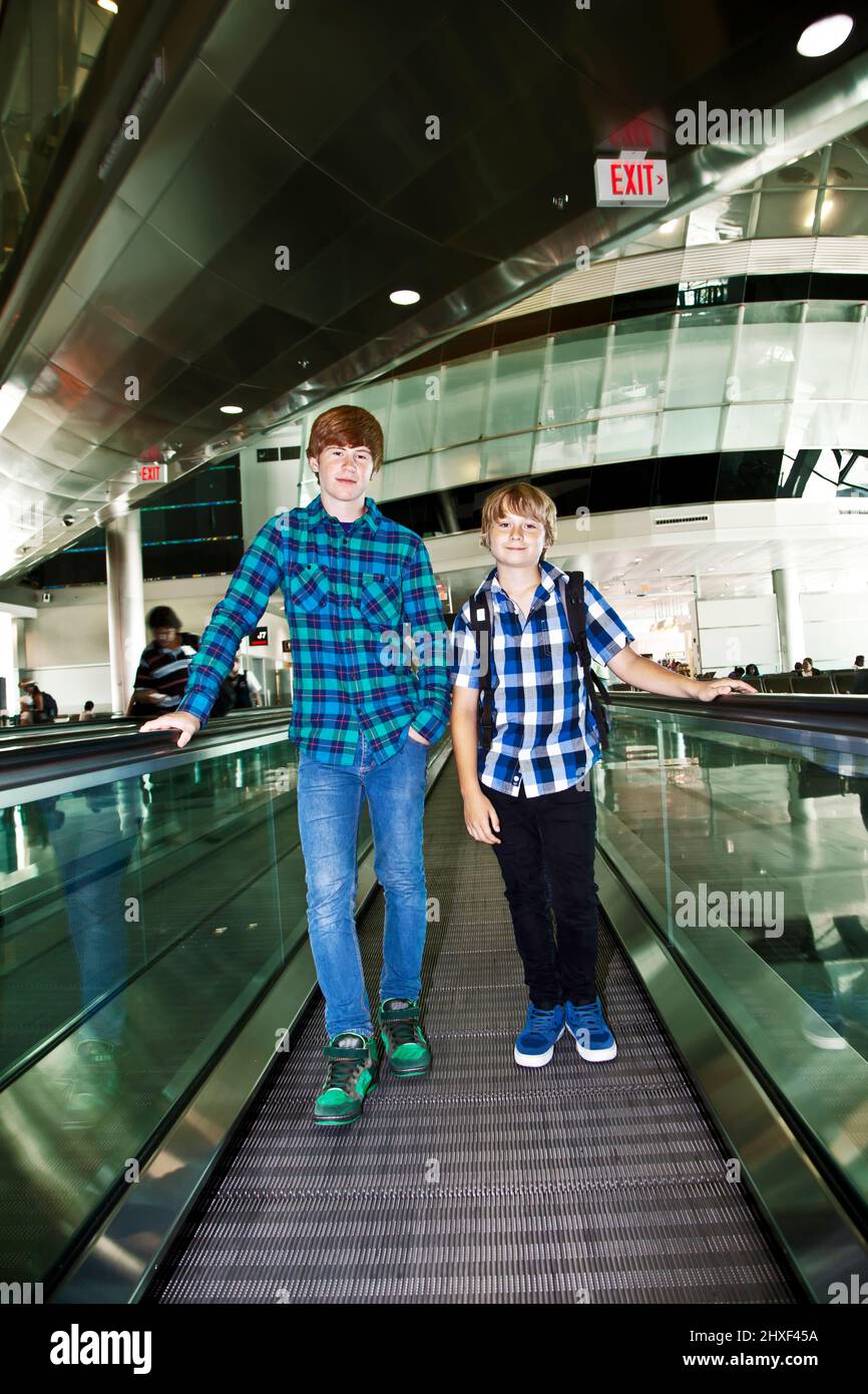young boys on a moving staircase at the airport Stock Photo - Alamy