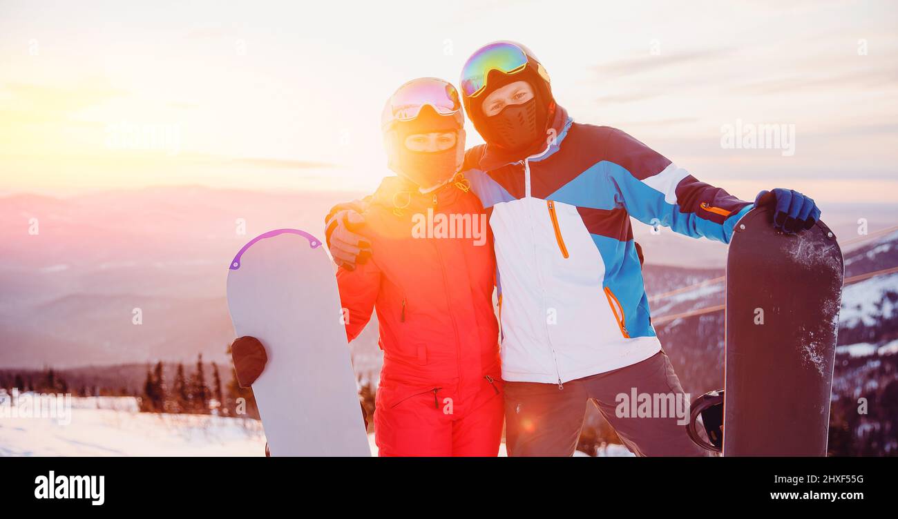 Happy couple man and woman snowboarders background sunset ski resort ...