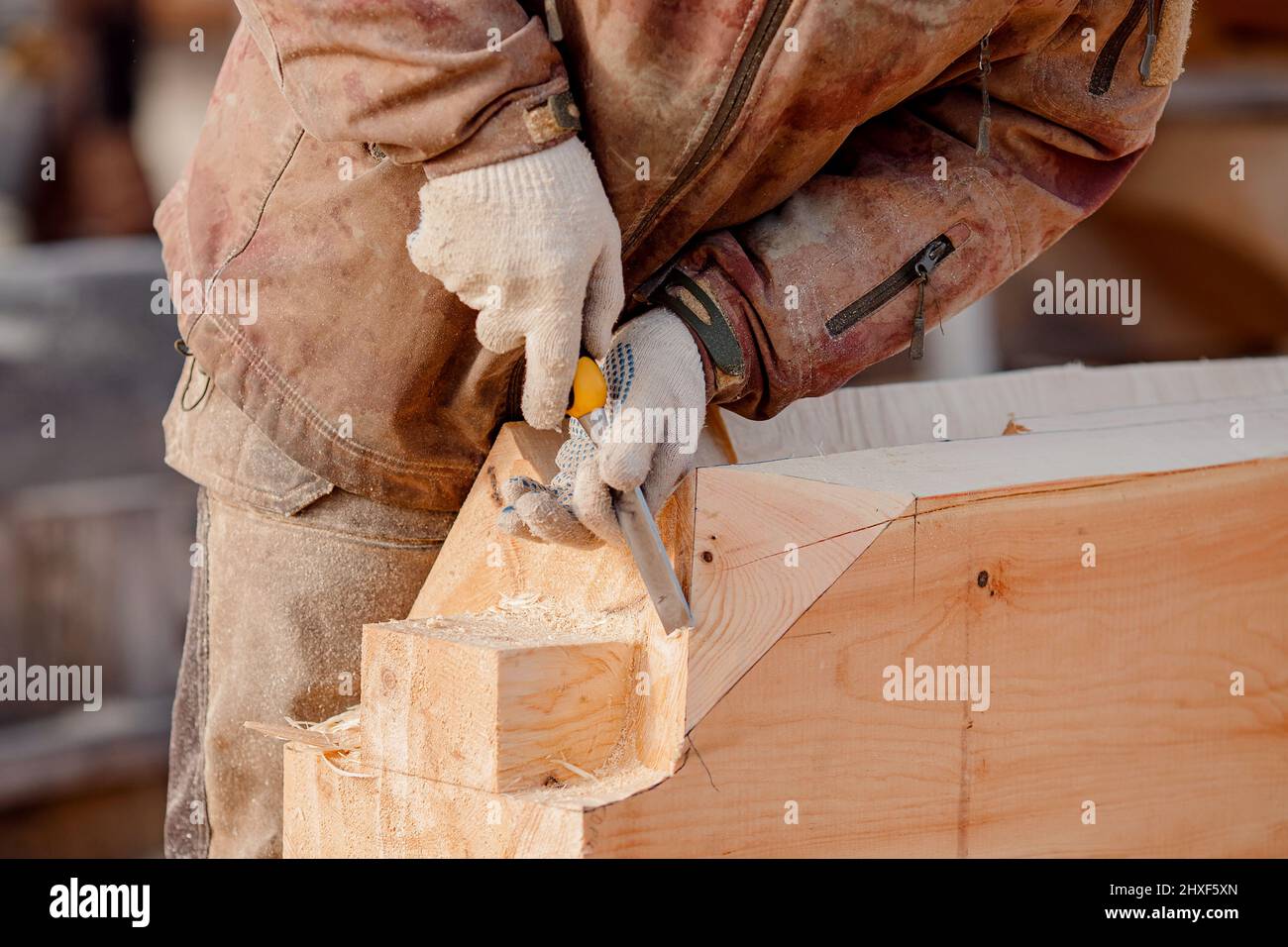 Industrial carpenter working with log, construction frame building site ...