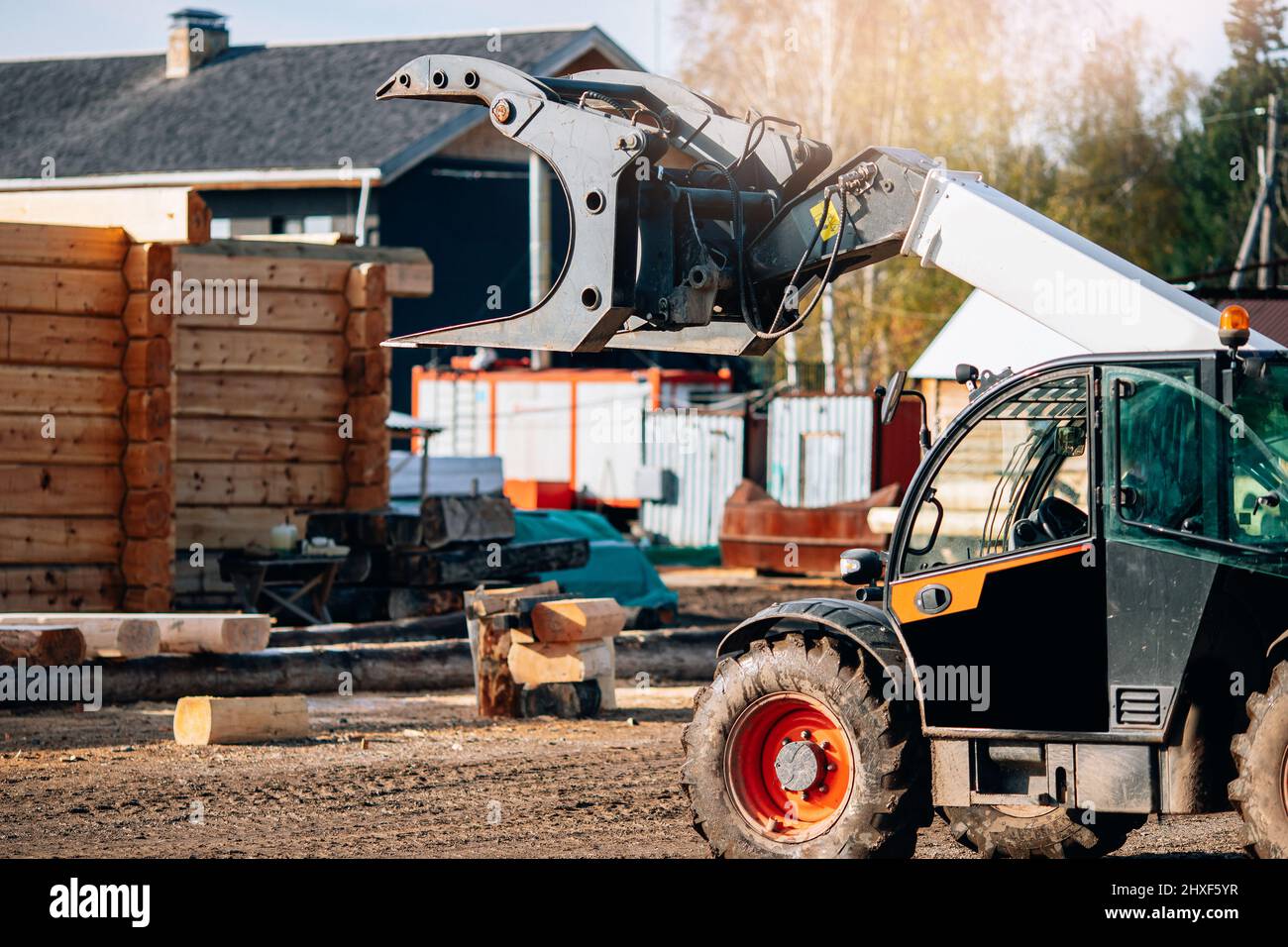 Loader carries logs against background of building wooden house Stock ...
