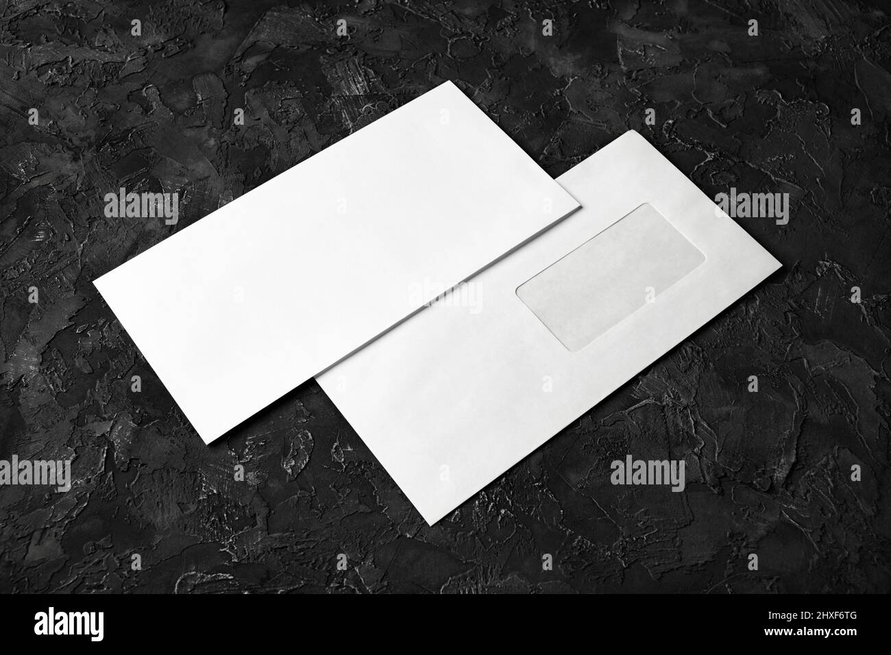Two blank envelopes on black plaster background. Front and back side ...
