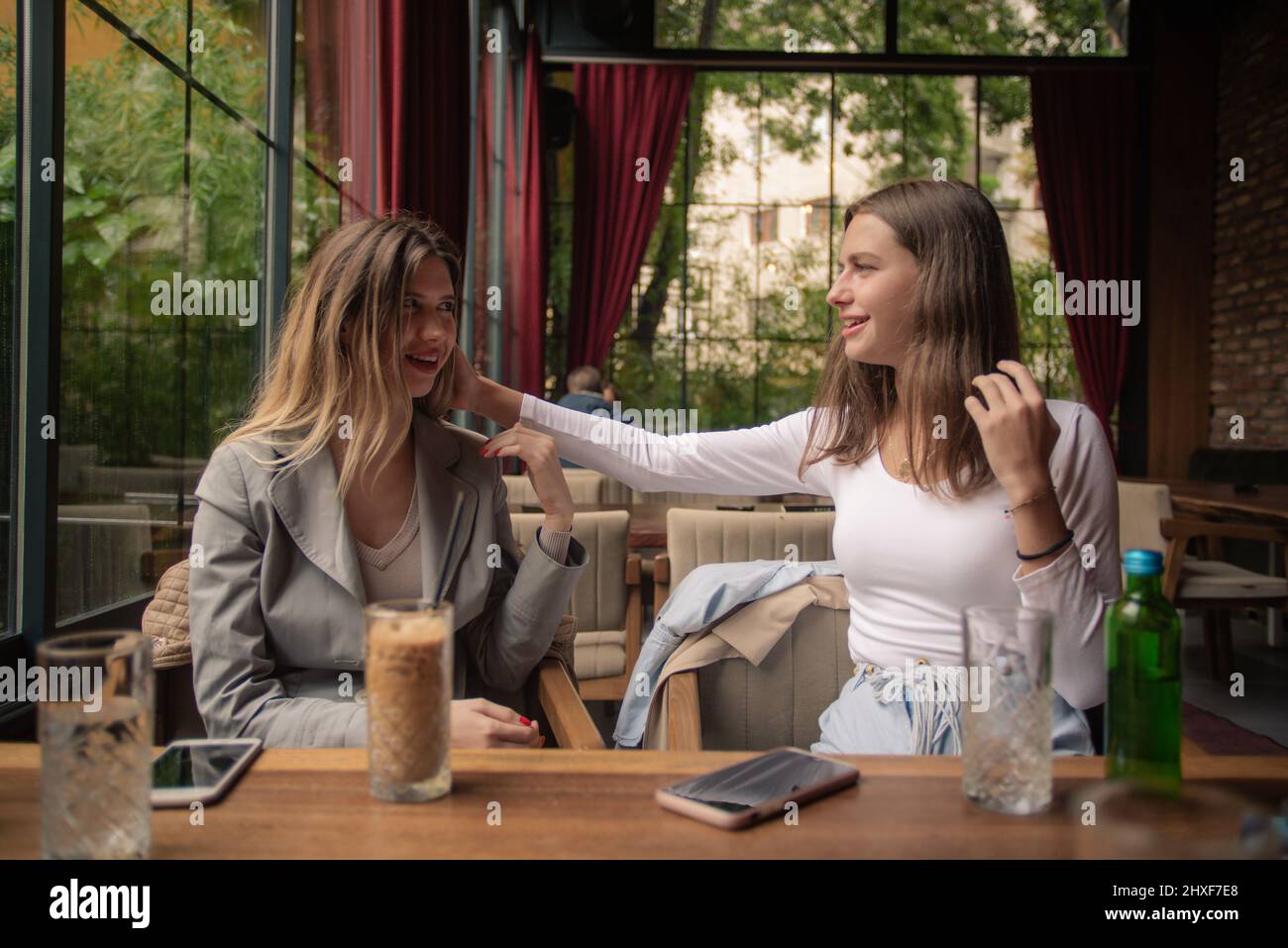 Young and beautiful girl is giving compliments to her sister while ...