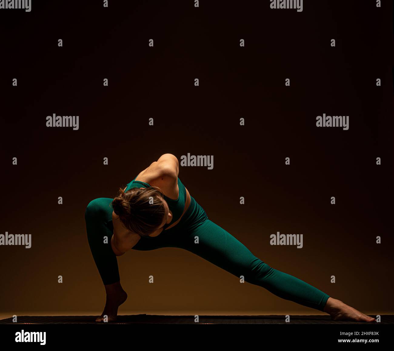 Attractive and beautiful young girl is stretching and twisting her body ...