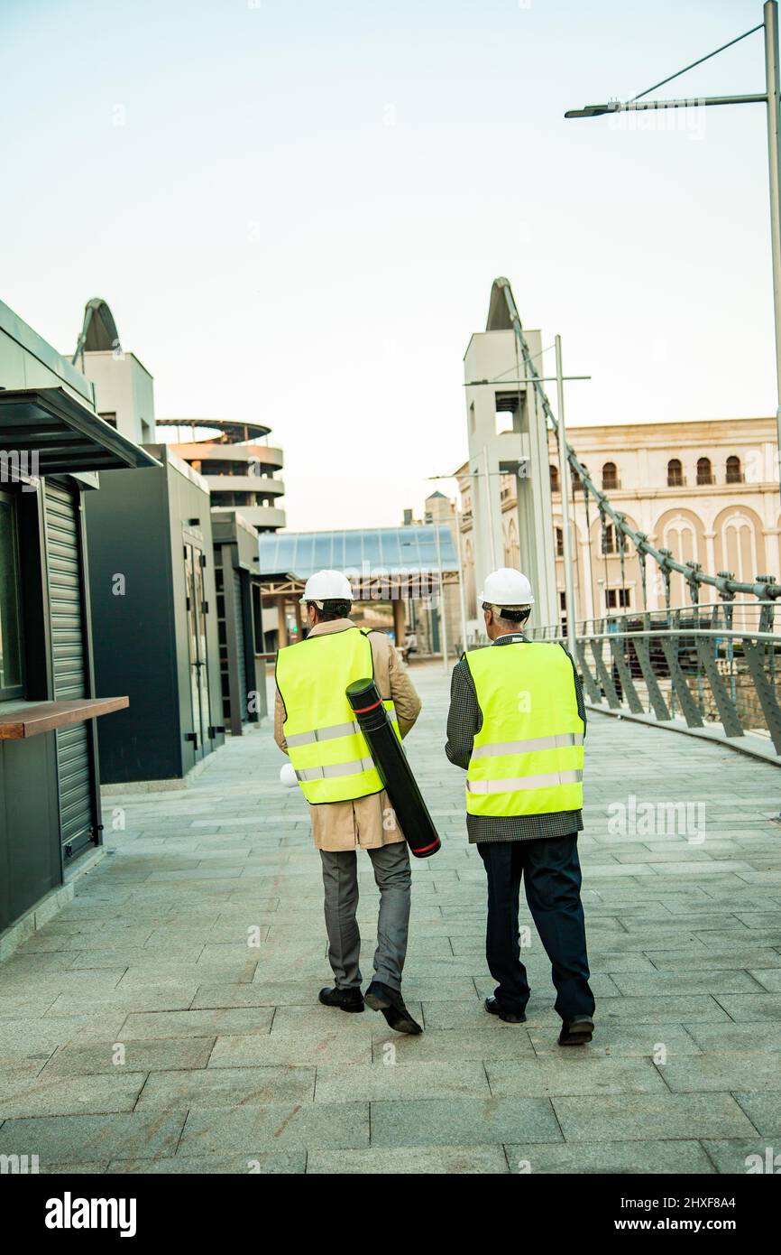 Two senior construction managers are walking and talking about the ...