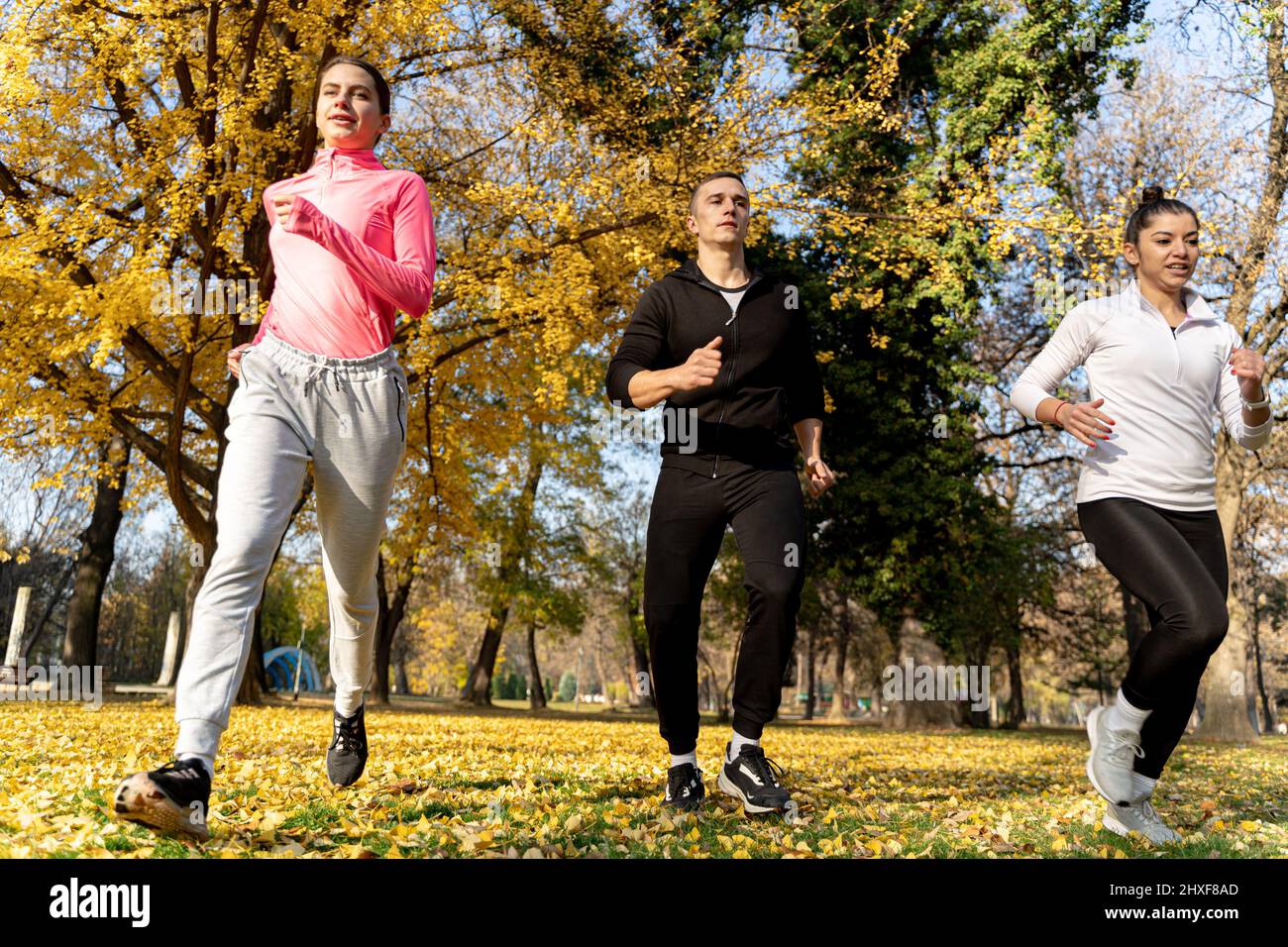 Three amazing and attractive fit friends are running and smiling, low ...