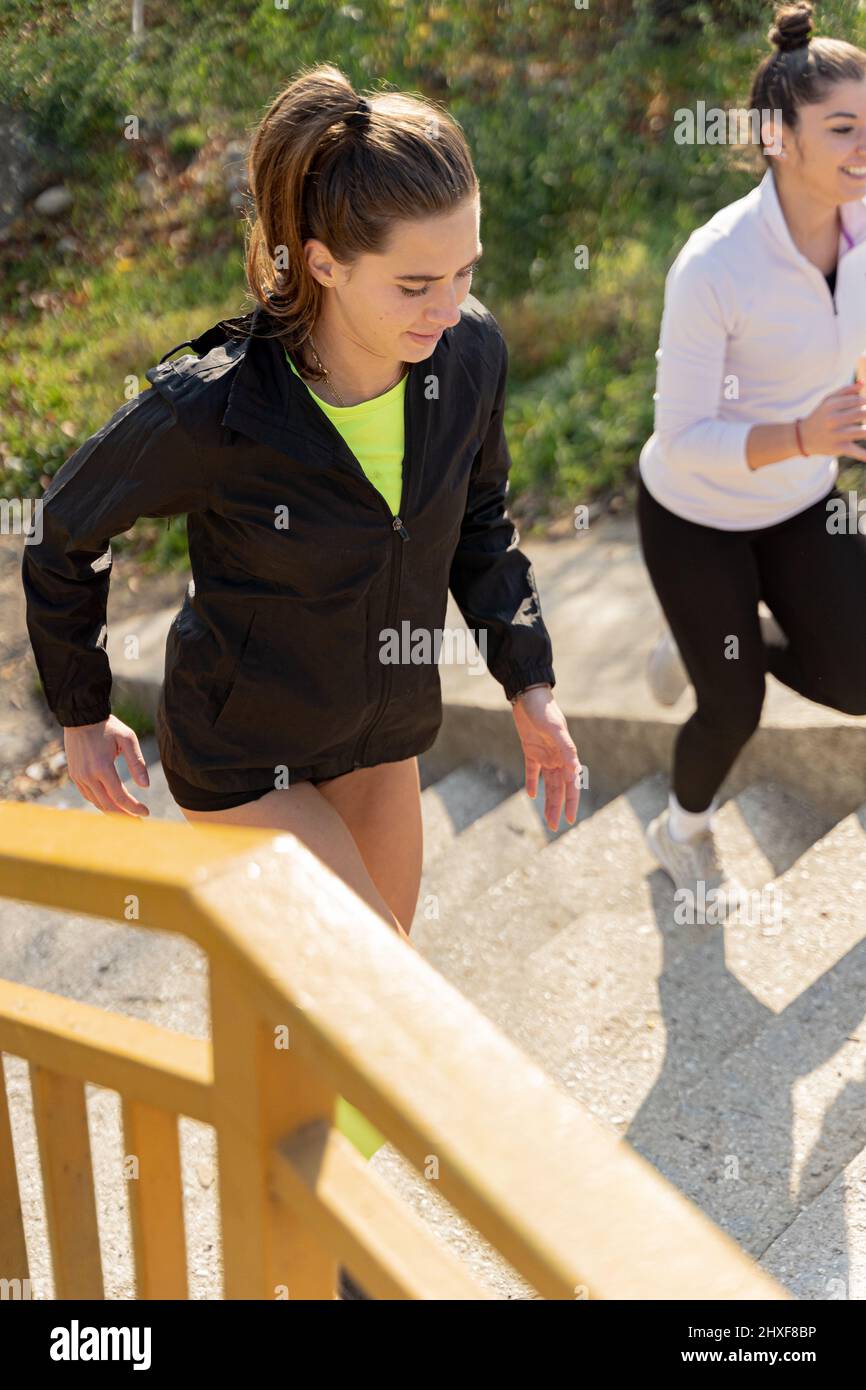 Three attractive and amazing fit friends are going up the stairs ...