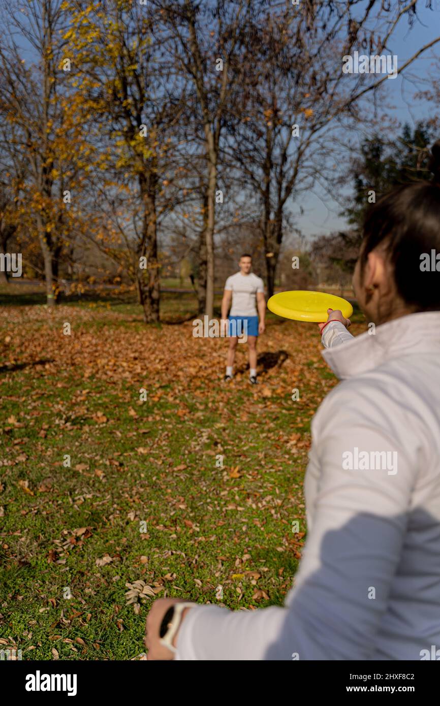 Two attractive and amazing fit friends are playing frisbee outside ...