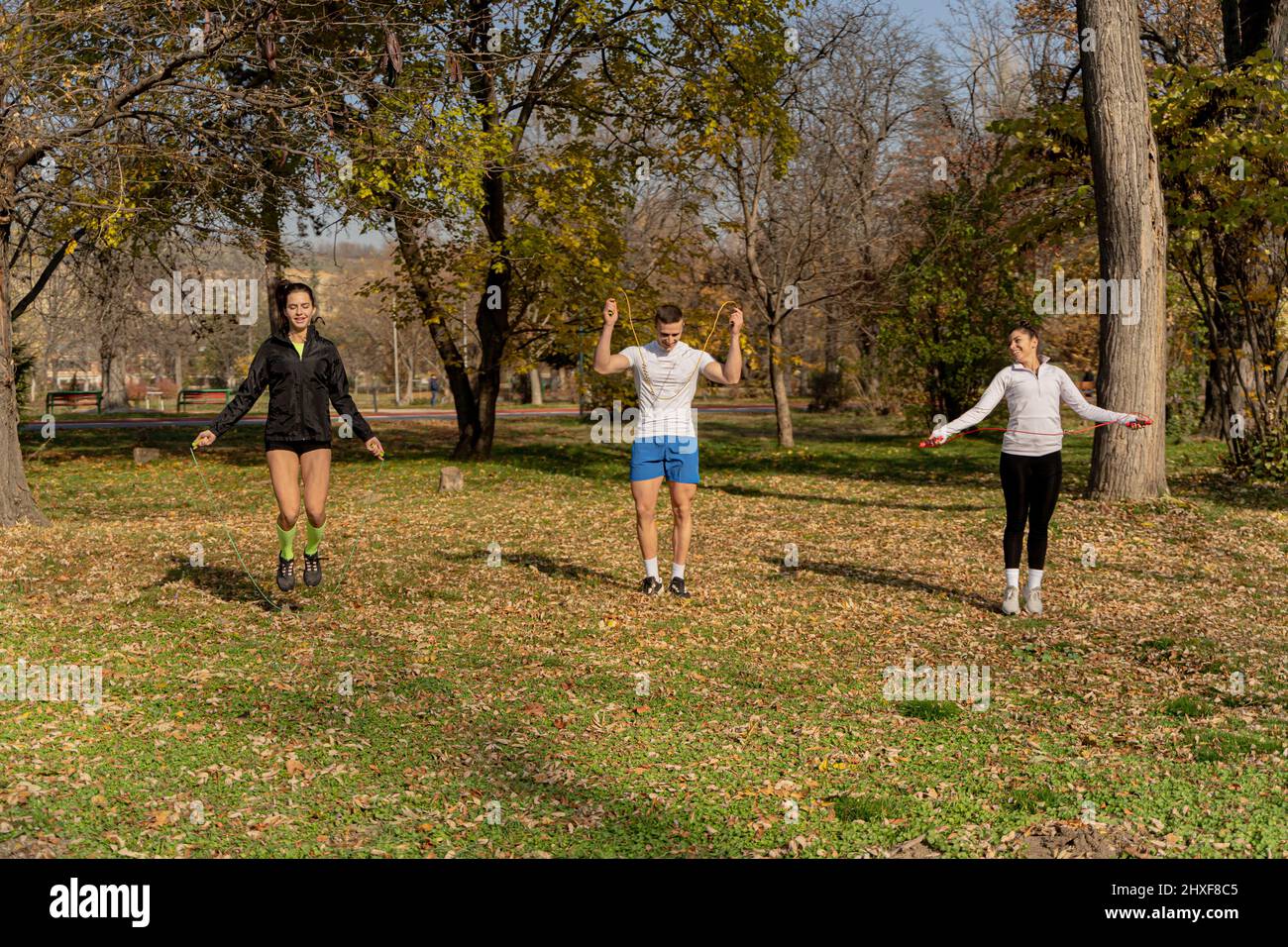 Three attractive and beautiful fit friends are jumping on the rope and ...