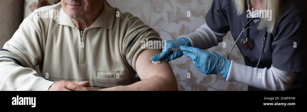 Doctor preparing vaccination shot to elderly patient by holding syringe ...