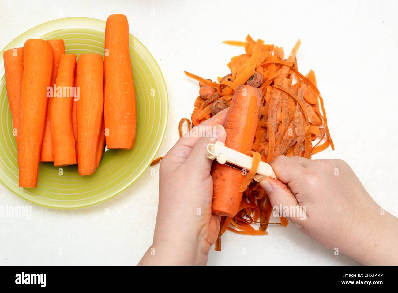 A woman peels carrots by cutting off the top layer of carrots. Cooking ...